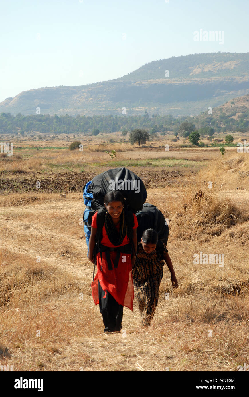 Girls carrying paragliders up slope in Western Ghats, Kamshet ...