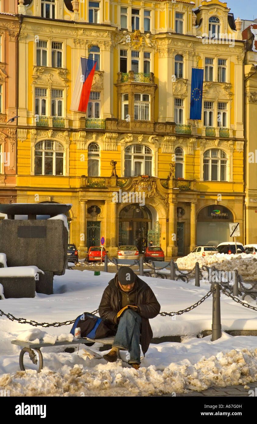 A man reading a book in snowy Old Town Square of Prague Czech Republic ...