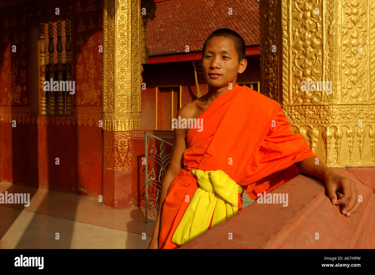 A young novice Buddhist monk stands in front of the beautiful Wat Saen ...