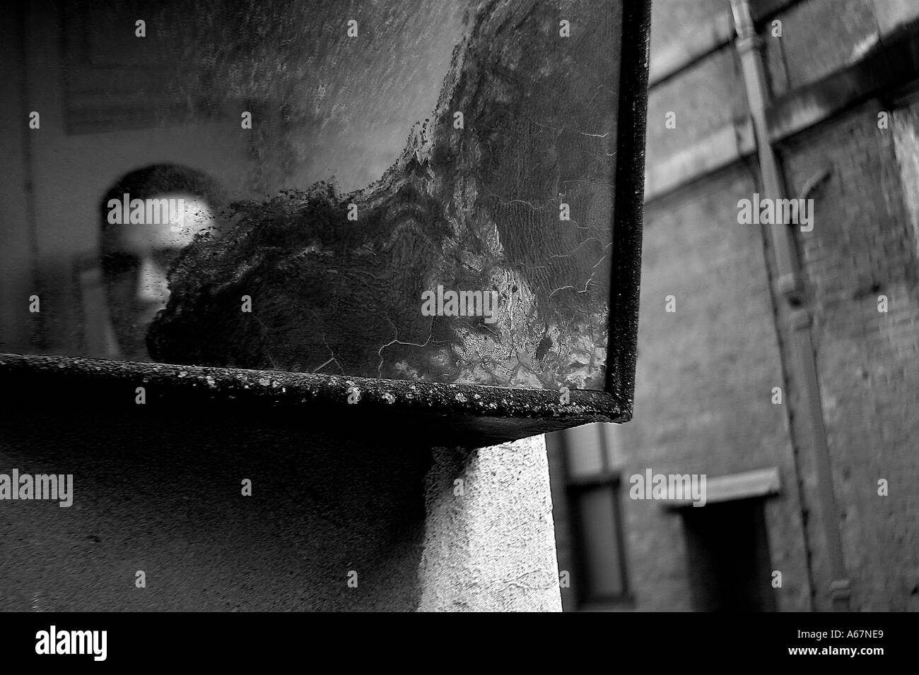 glimpse of man in old mirror in an alley doorway in black and white ...