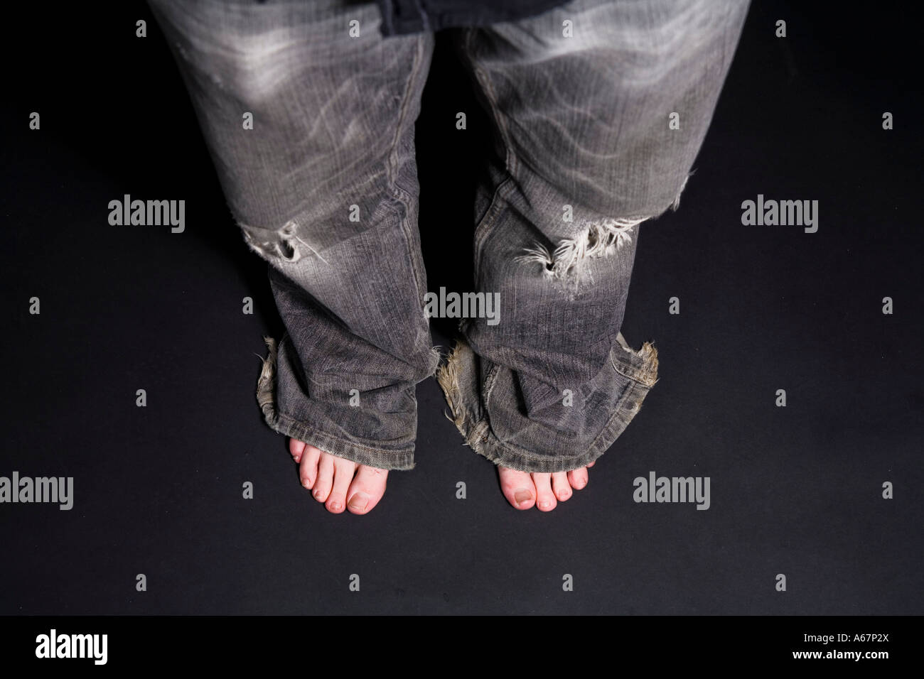 Legs only shot with scruffy ripped jeans and bare feet male Stock Photo ...