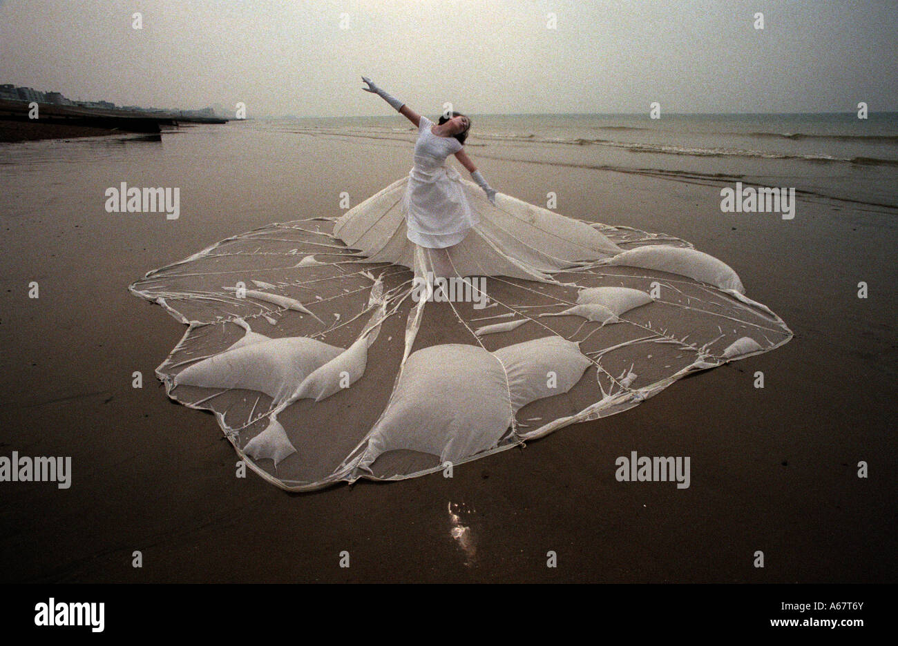 One Girl Dances Alone On A Beach In Huge Billowing Wet White Dress And Long White Gloves Stock