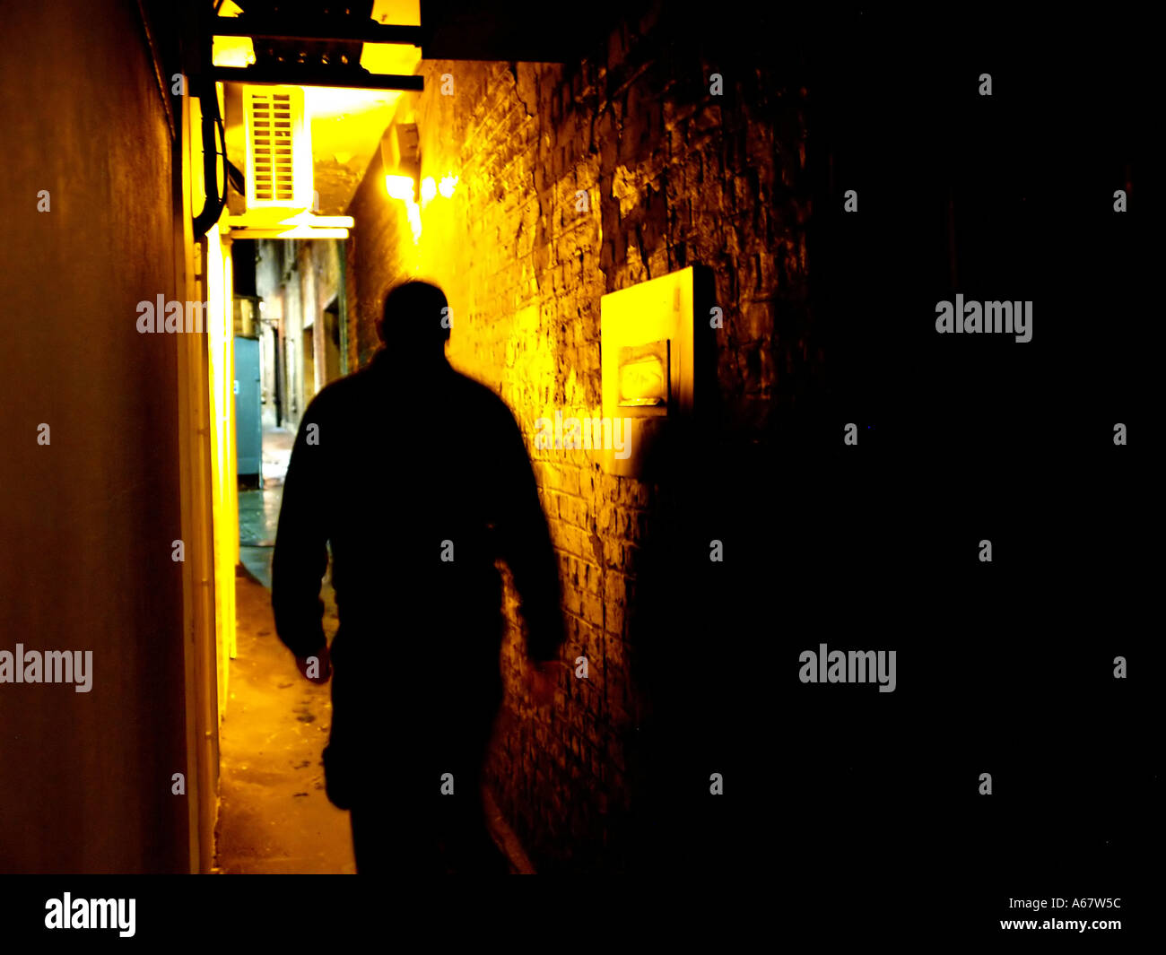 silhouette of man running through alleyway at night Stock Photo - Alamy
