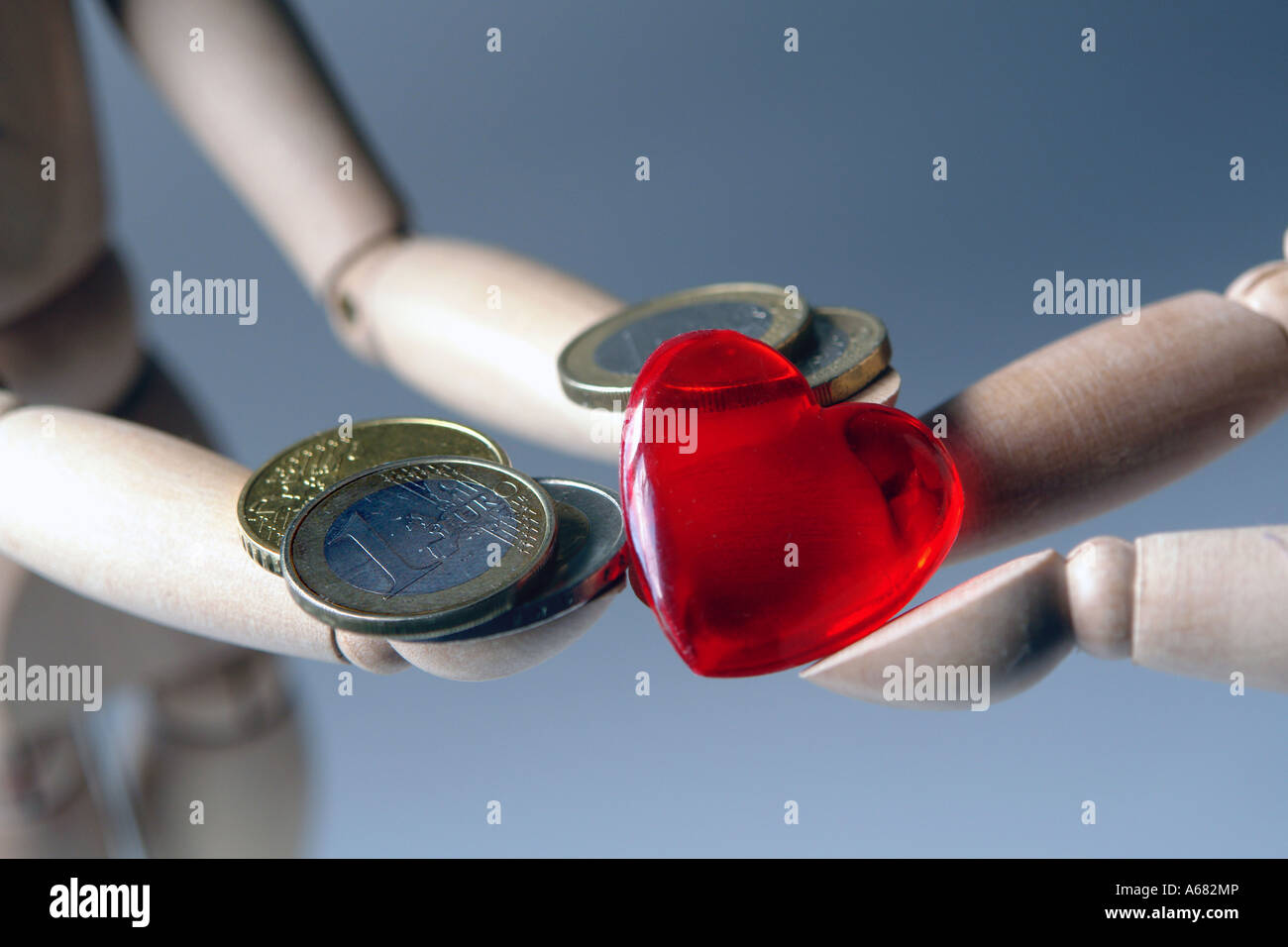 Two wooden figures giving each other a red heart and a Euro coin Stock ...