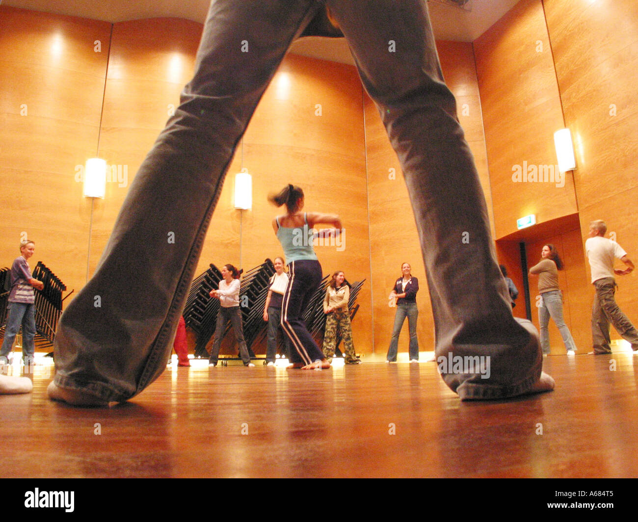teenage schoolkids taking a class in African dancing seen through legs ...
