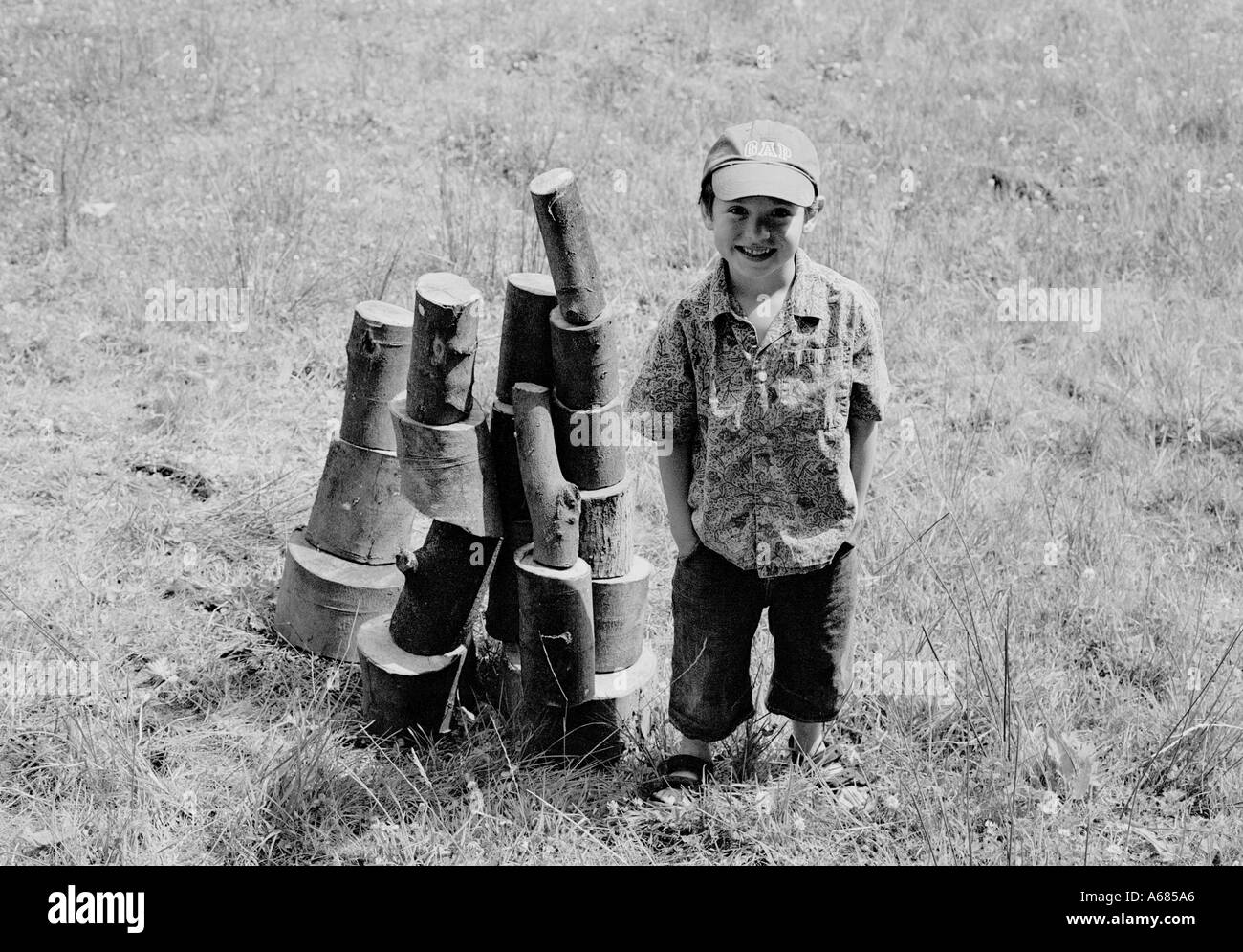 small boy standing next to a pile of logs Stock Photo - Alamy