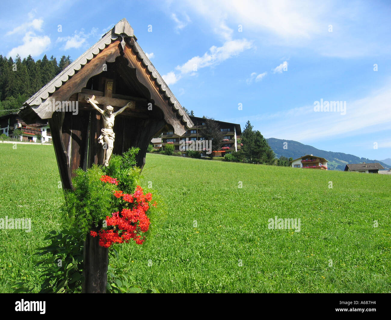 single roadside cross with red flowers and Jesus figure between ...