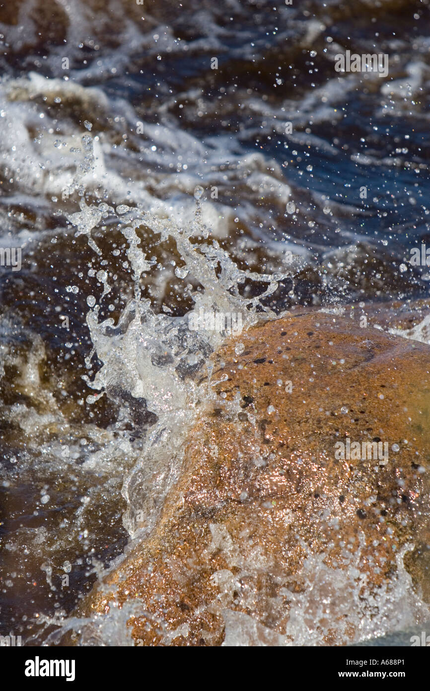 Waves splashing against small rock in water Stock Photo - Alamy