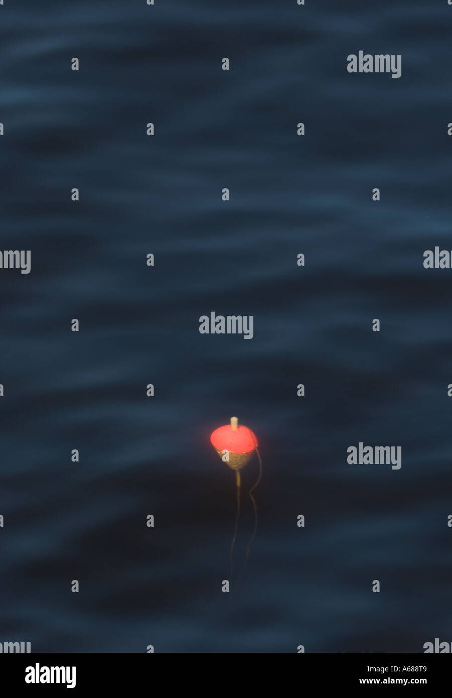 Bright red float submerged in dark black water Stock Photo - Alamy