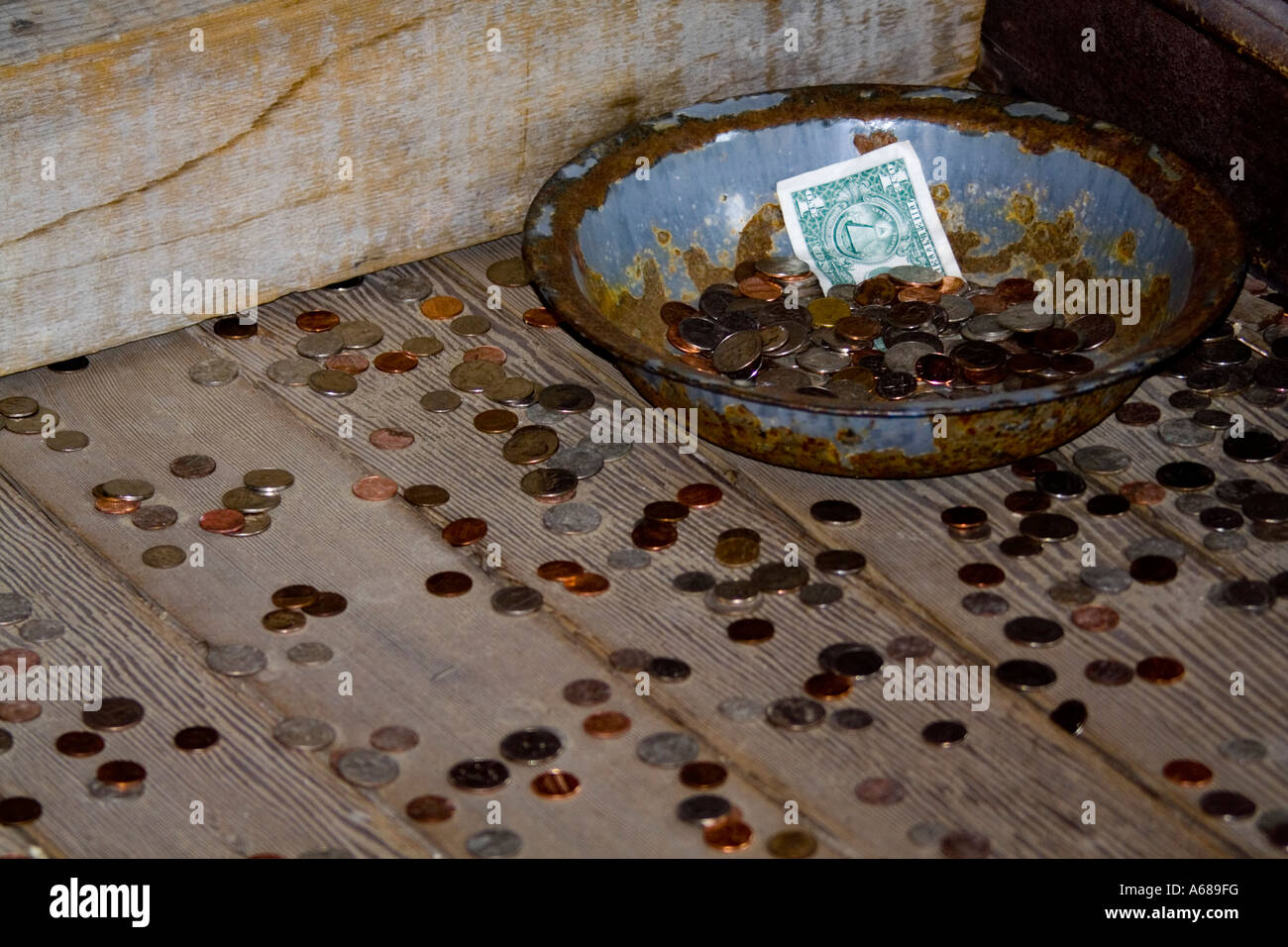 Rusty old pan containing change and a one dollar bill on a floor ...