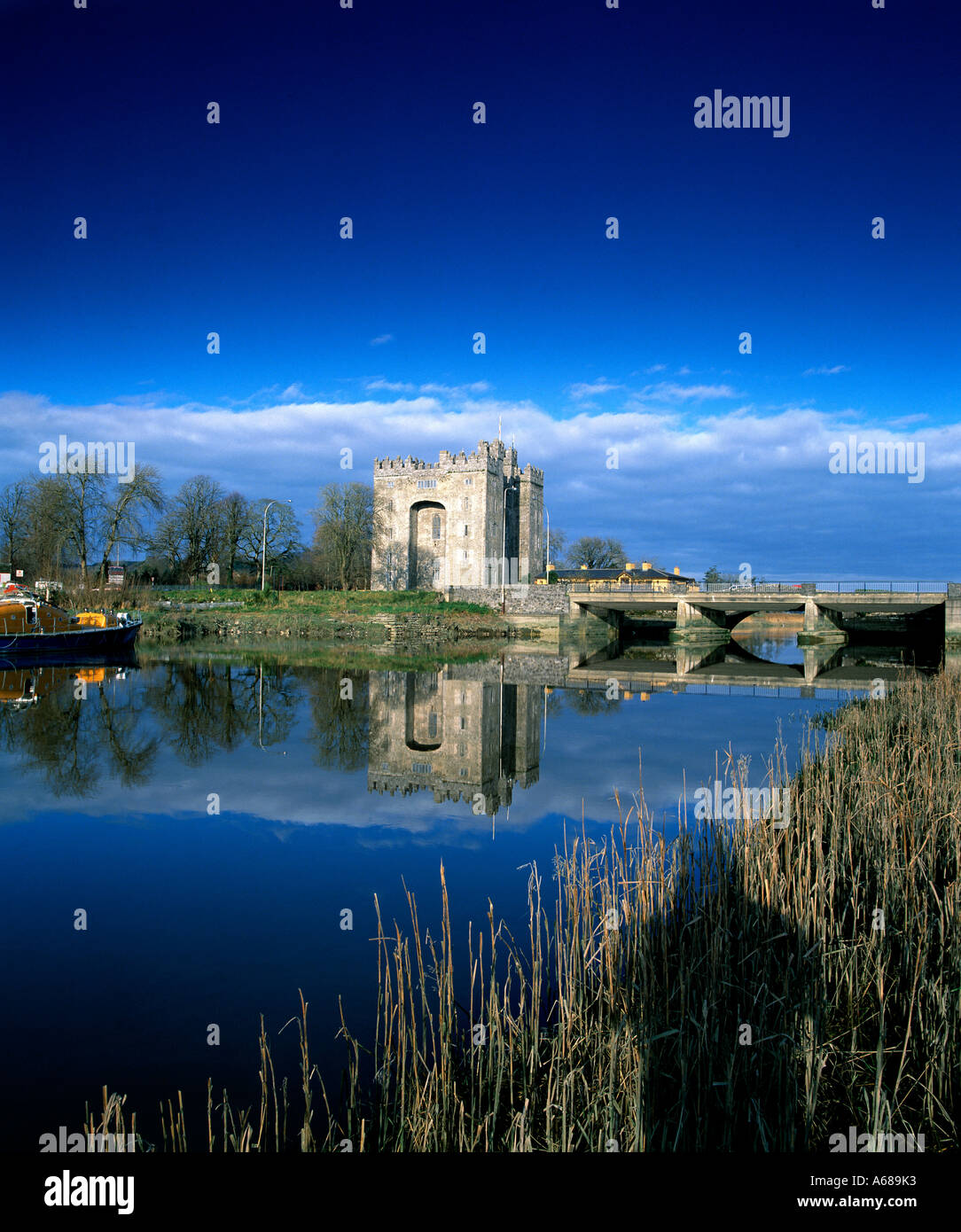 large stone built castle reflected on the calm waters of an irish river ...