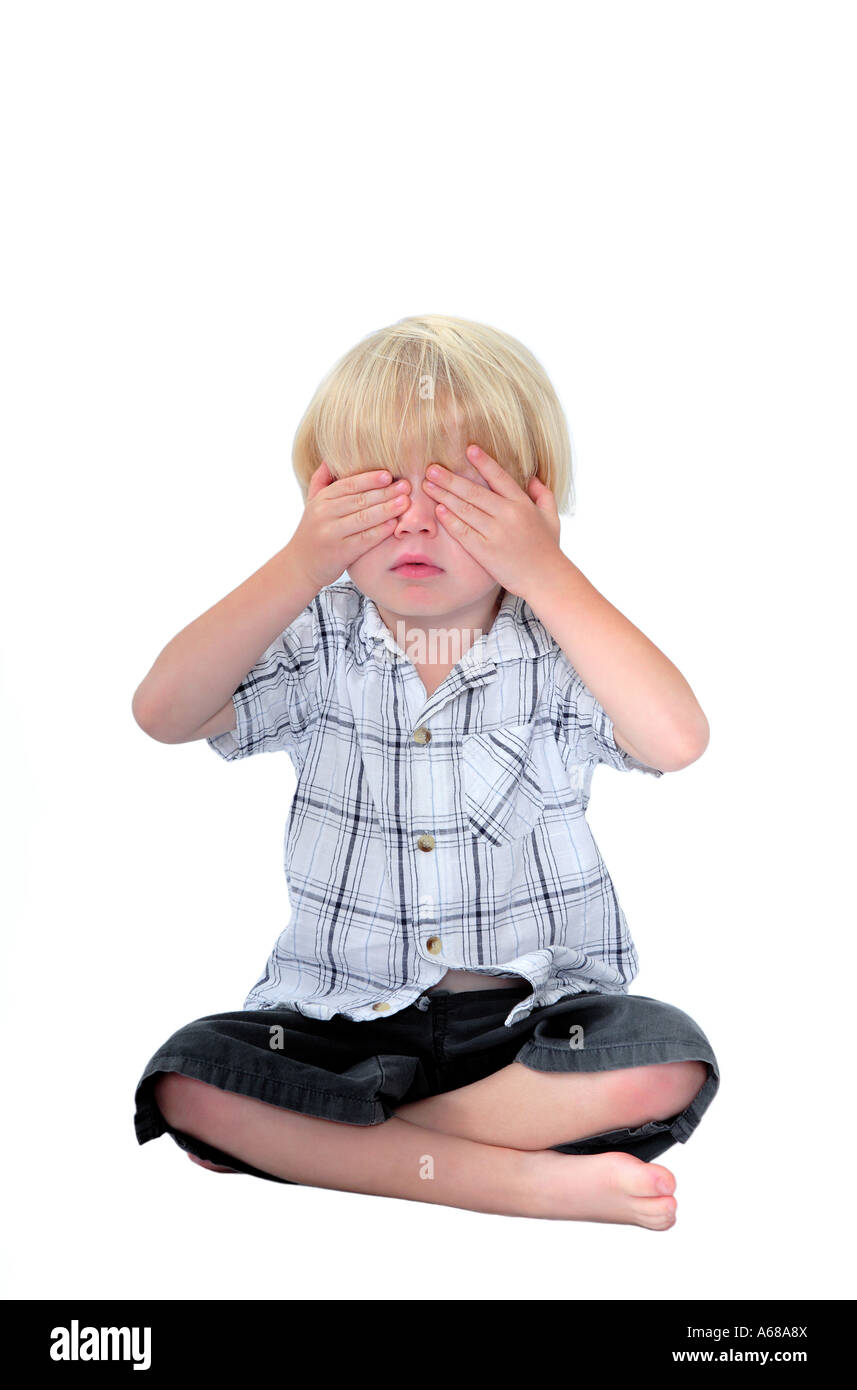 Studio photo of young boy with his hands over his eyes in anticipation ...