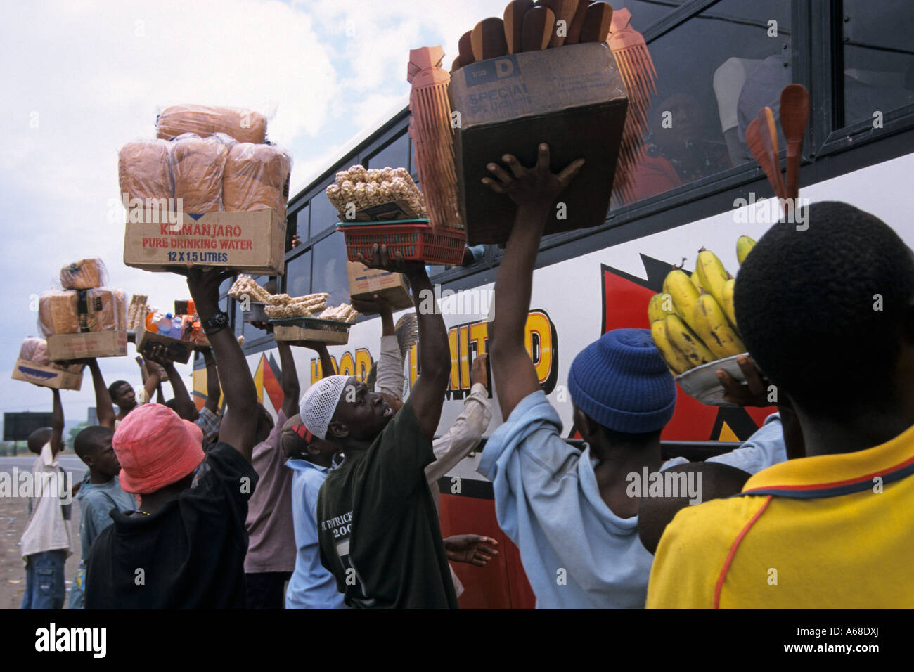 Street hawkers competing to sell refreshments to bus passengers at a ...