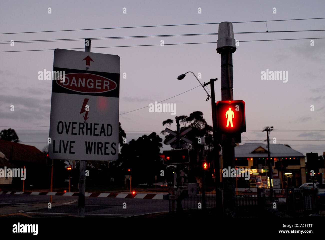 Railway crossing and boom gates at night, with "Danger overhead live ...