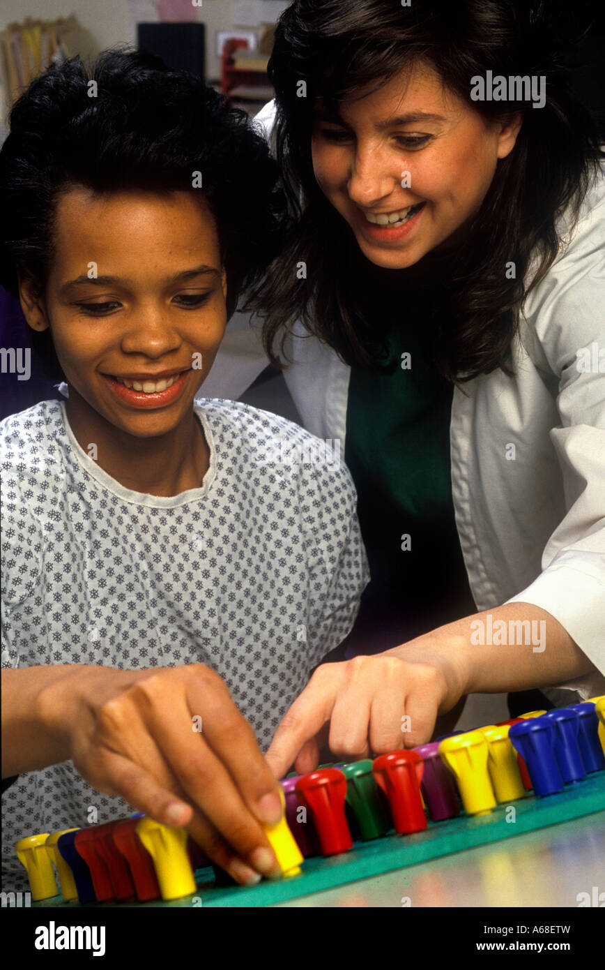 Physical therapist with patient working on motor skills at a peg board ...