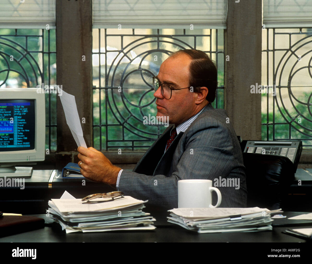Executive reviews paperwork in his corporate office Stock Photo - Alamy