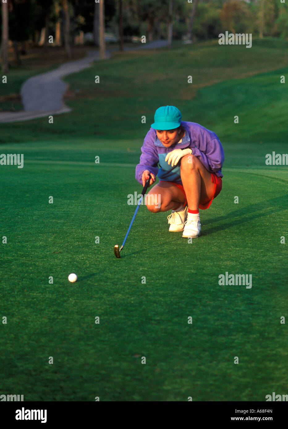 Woman golfer lining up a putt Stock Photo - Alamy