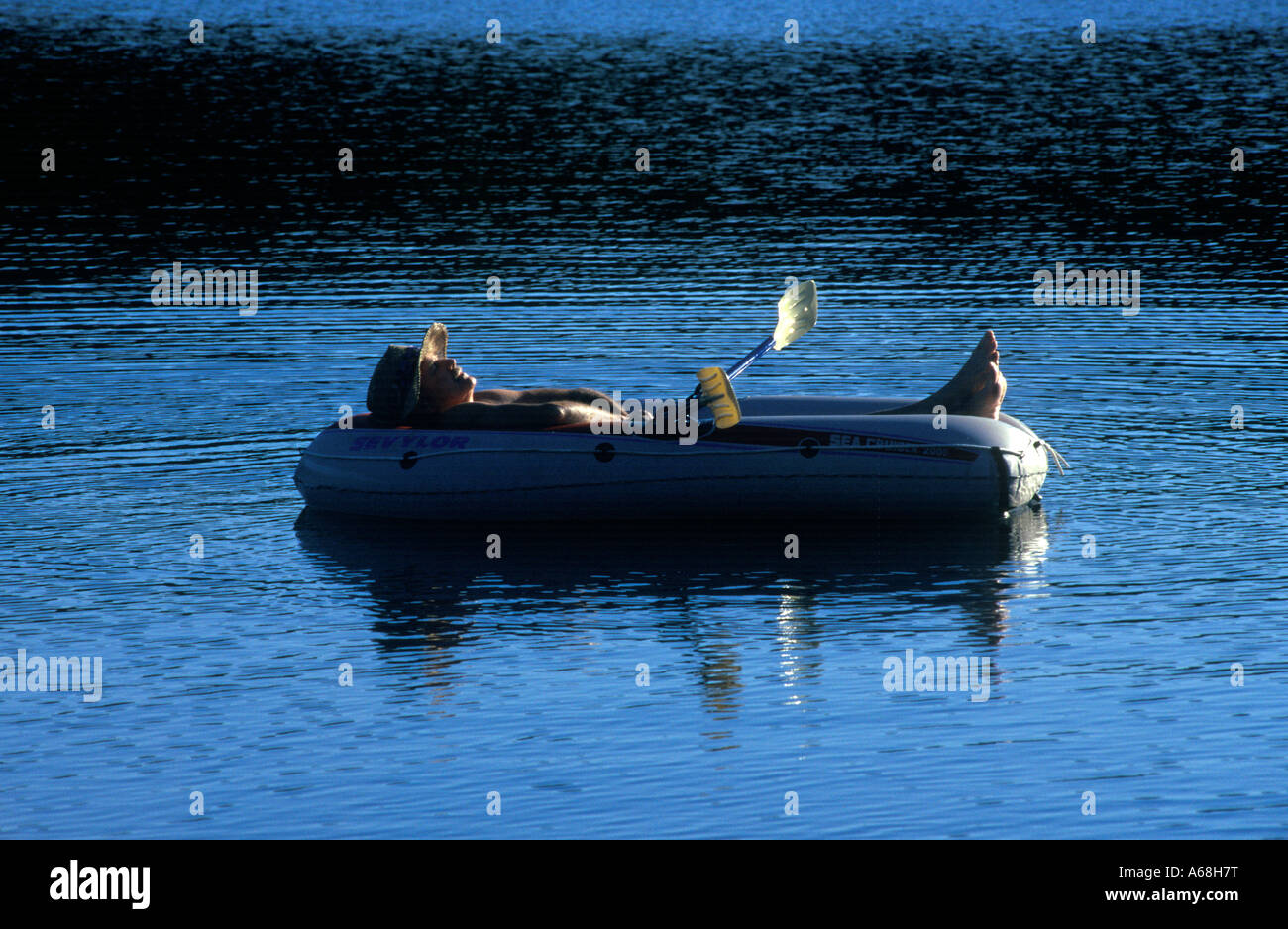 Senior man relaxes in an inflatable raft boat on a lake Crystal Lake ...