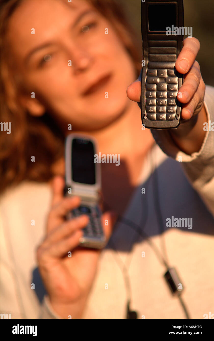 Young girl showing two cellular phones outside, with sunset light Stock ...