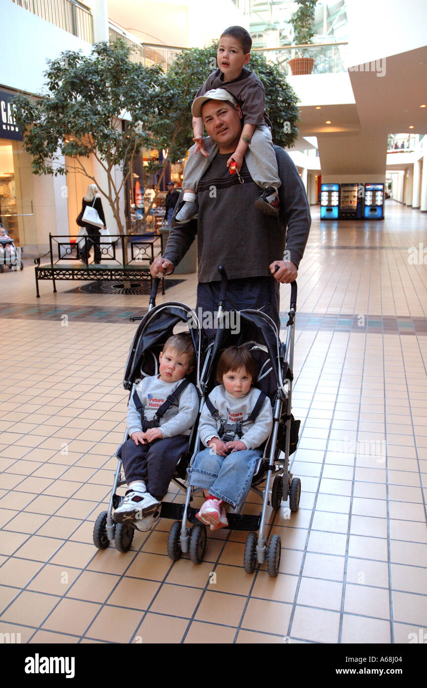Father out shopping with his twins and young son Stock Photo - Alamy