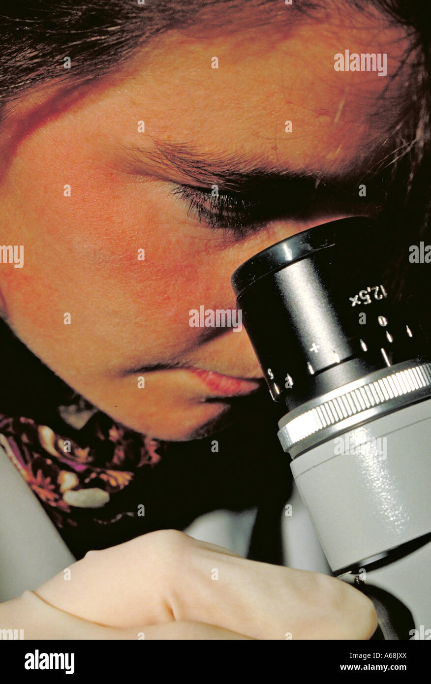 Woman looking through a microscope Stock Photo - Alamy