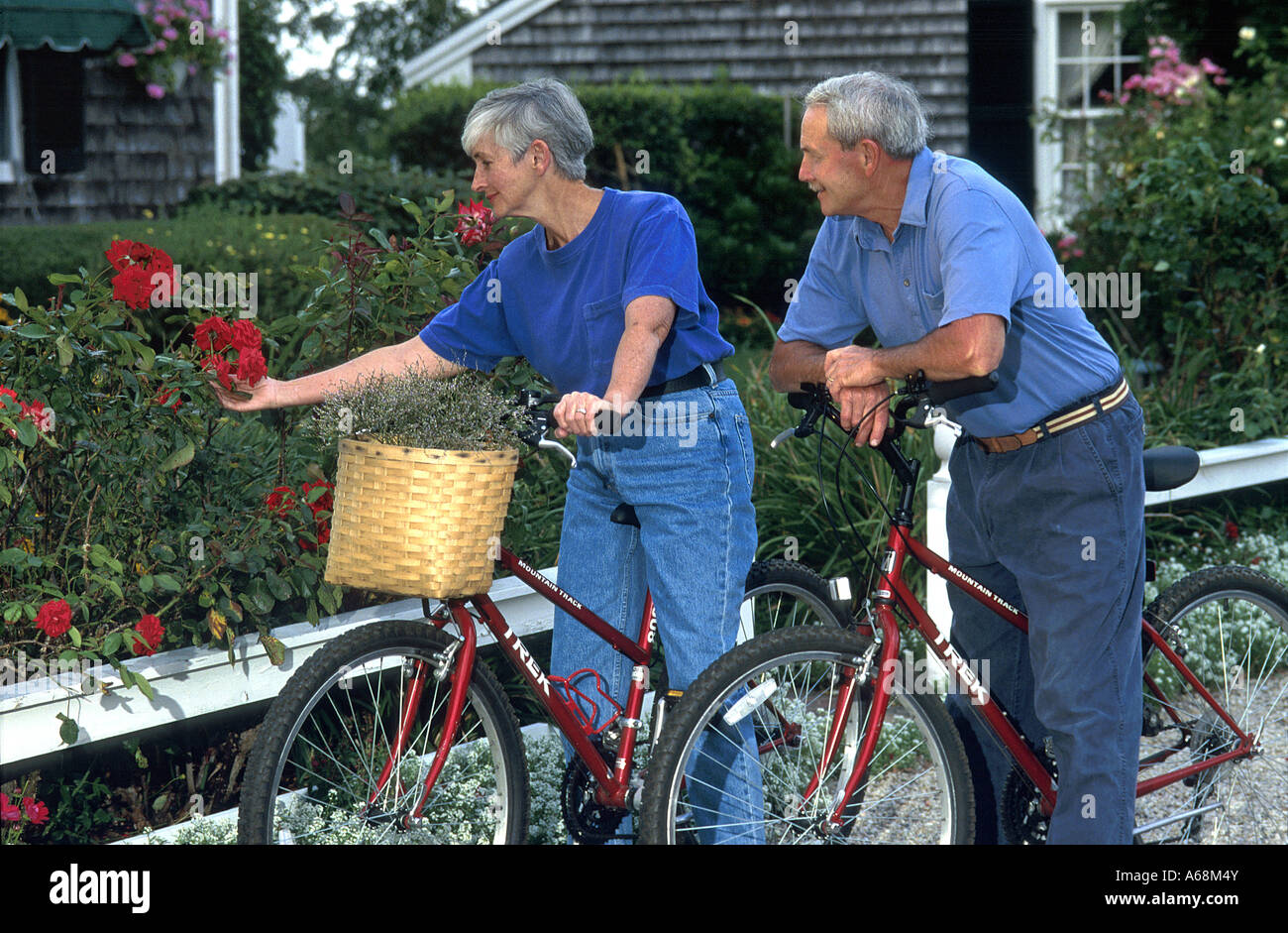 Senior couple stops to smell the roses while on a bike ride Stock Photo ...