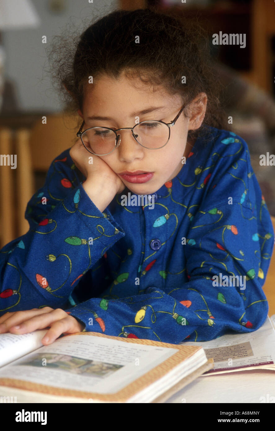 Portrait of a young girl wearing glasses as she reads while doing her ...