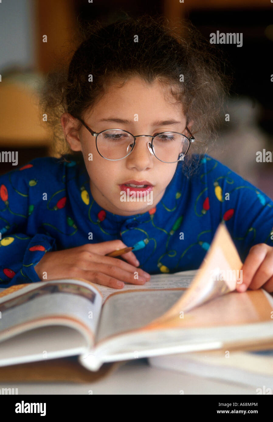 Portrait of a young girl wearing glasses as she reads while doing her ...