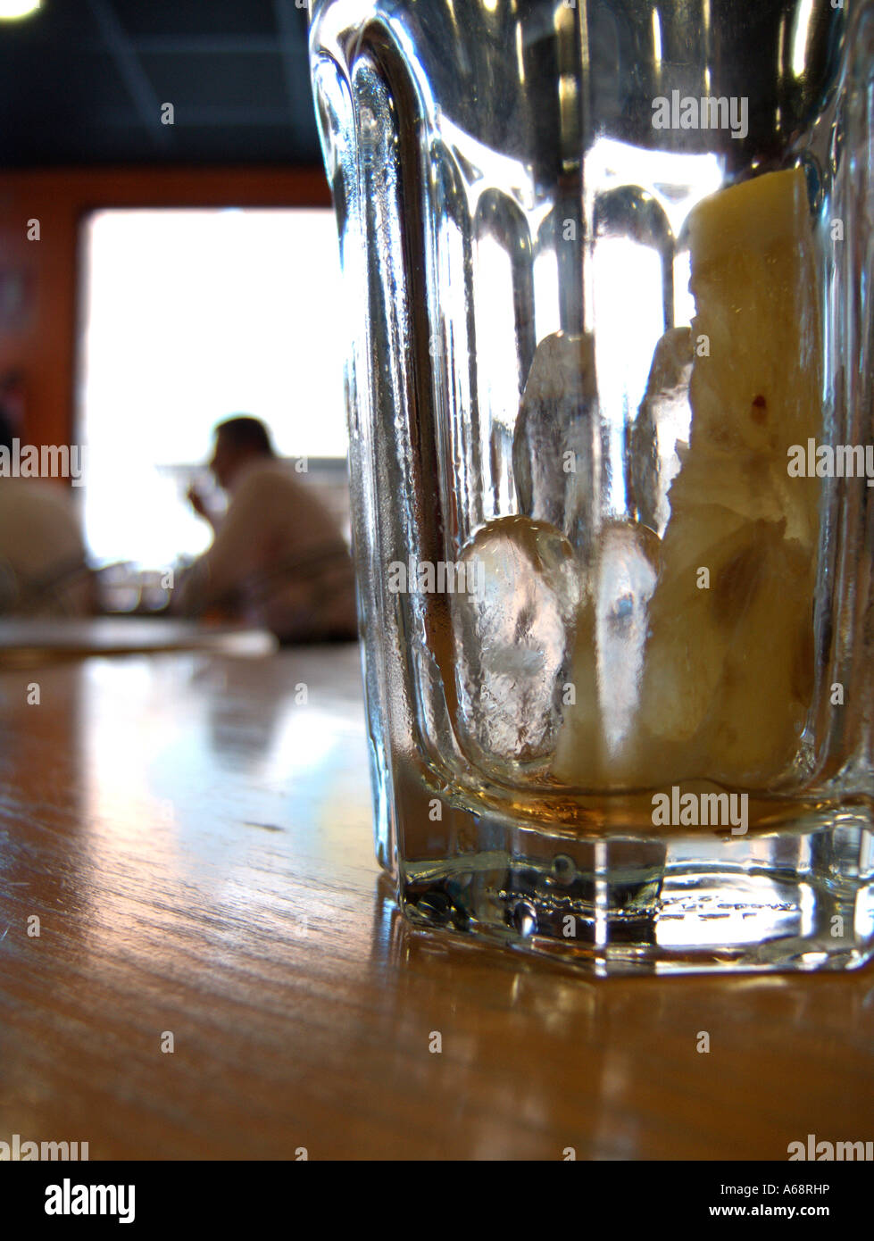Closeup of an empty glass and people talking on a table Stock Photo - Alamy