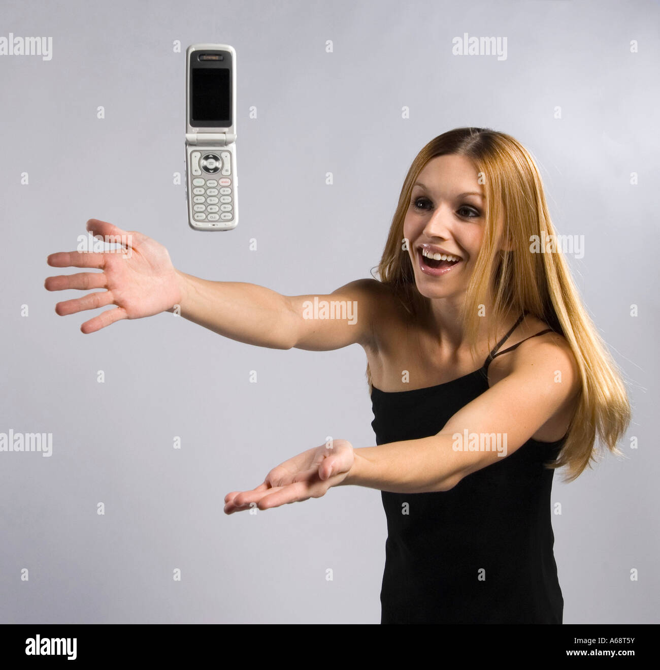 Woman in elegant black dress trying to catch a cell phone that is ...