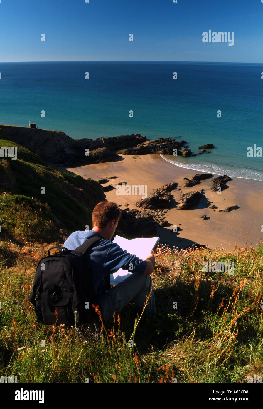 A man reading a map overlooking the South West coast at Whitsand bay ...