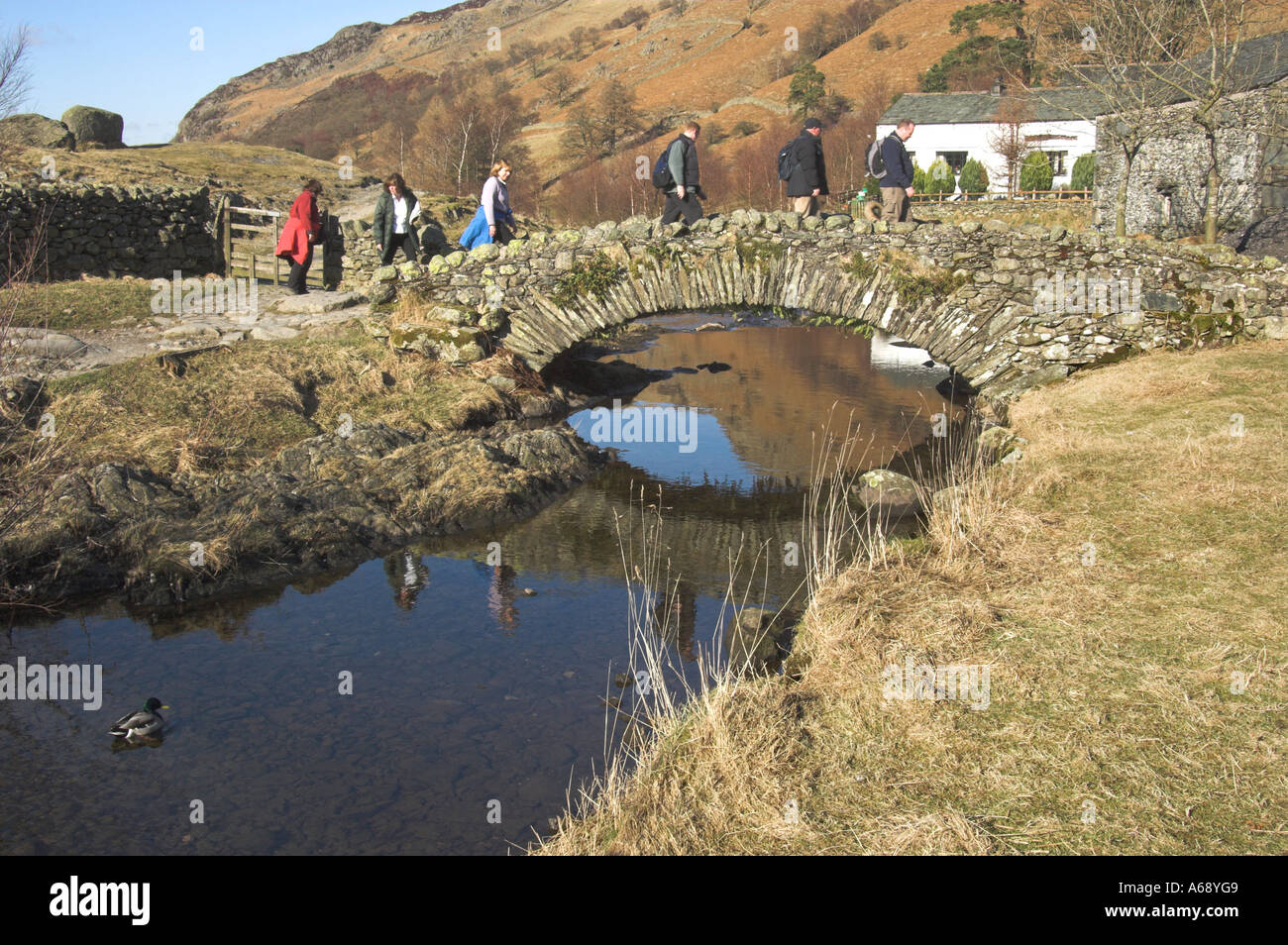 Walkers crossing pack horse bridge at Watendlath Tarn Stock Photo - Alamy