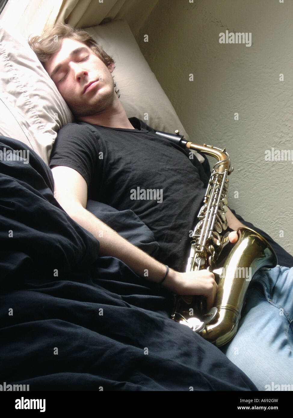 Portrait of Sleeping Man Lying in Bed With a Saxophone He is Wearing ...