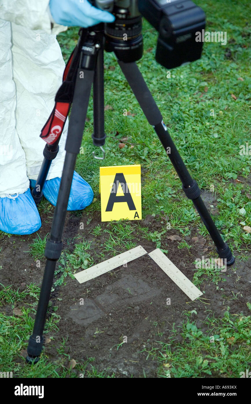 Crime scene officer photographically recording shoe print at crime ...