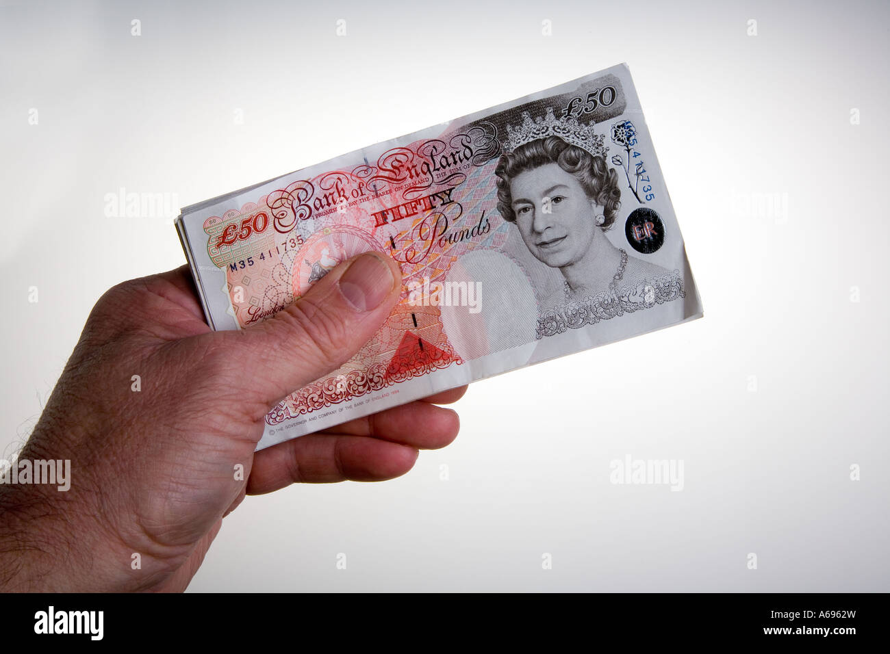 Hand holding fan of fifty 50 pound notes Stock Photo - Alamy