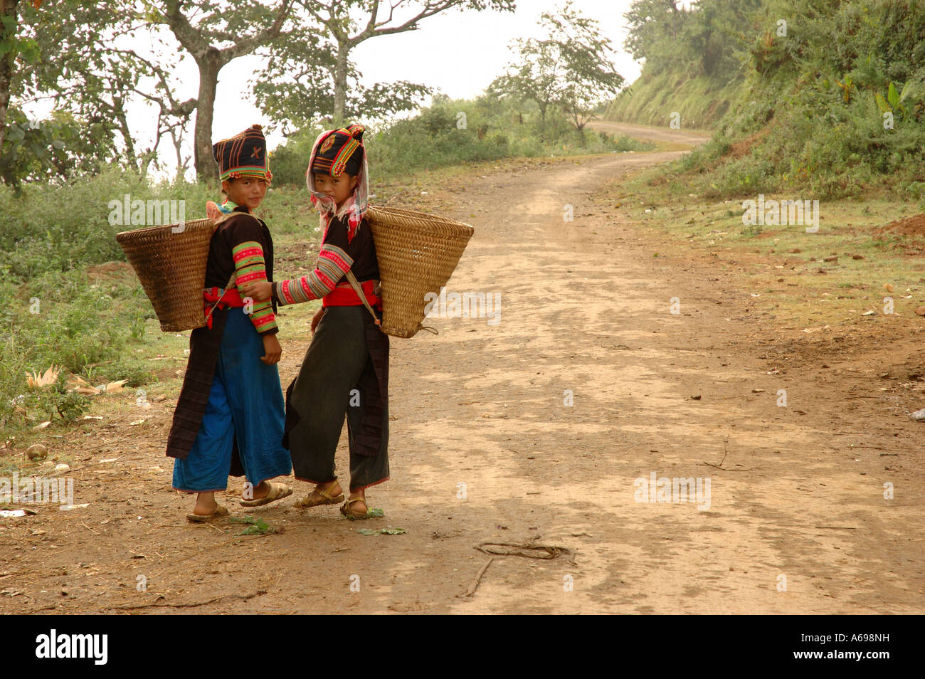 Two Blue Hmong indigenous girls in traditional cloth carry their ...