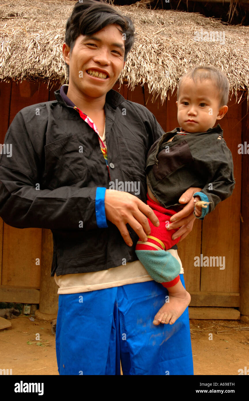 A Blue Hmong indigenous man wearing traditional cloth carries his son ...