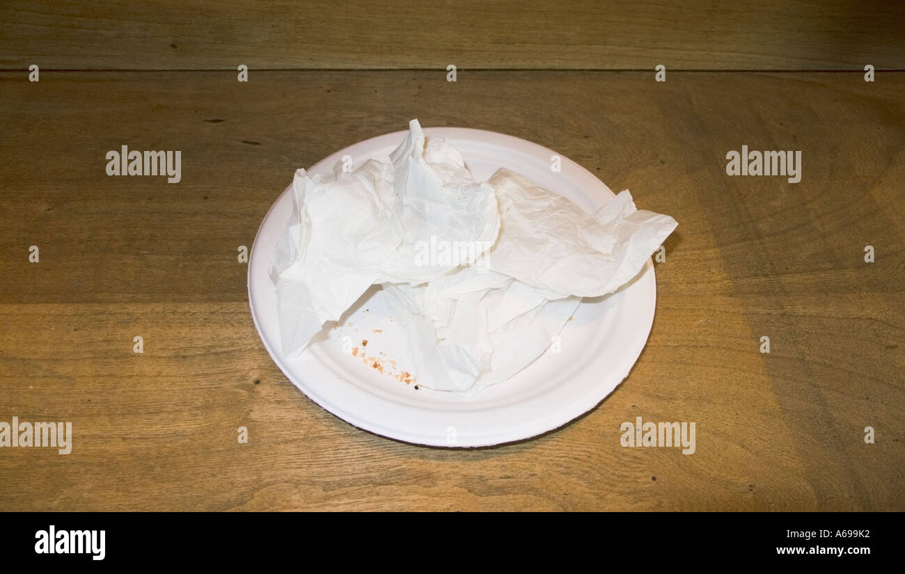Paper plate with screwed up napkin and bread crumbs on wood table Stock ...