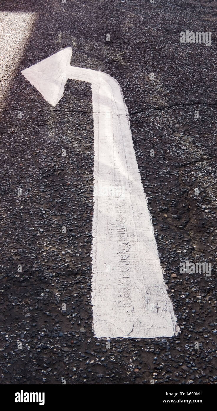 White arrow on road indicating left turn Stock Photo - Alamy