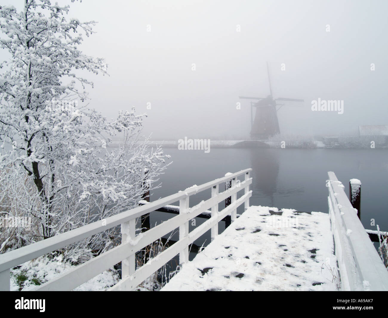 Dutch winter landscape with water tree with snow and windmill ...