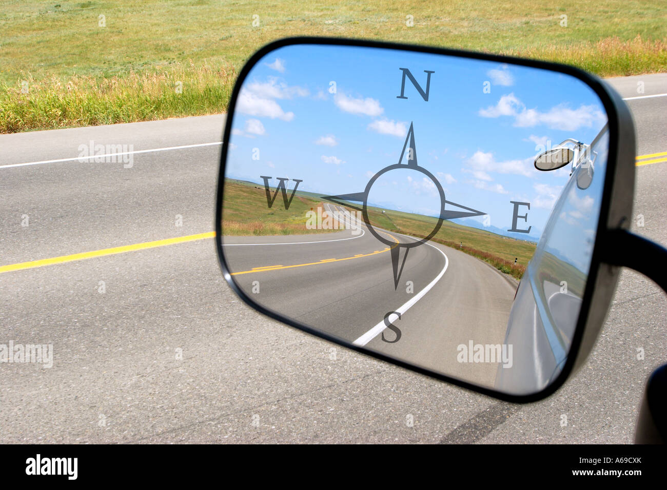 Side mirror on cargo van reflecting highway road with compass symbol in ...