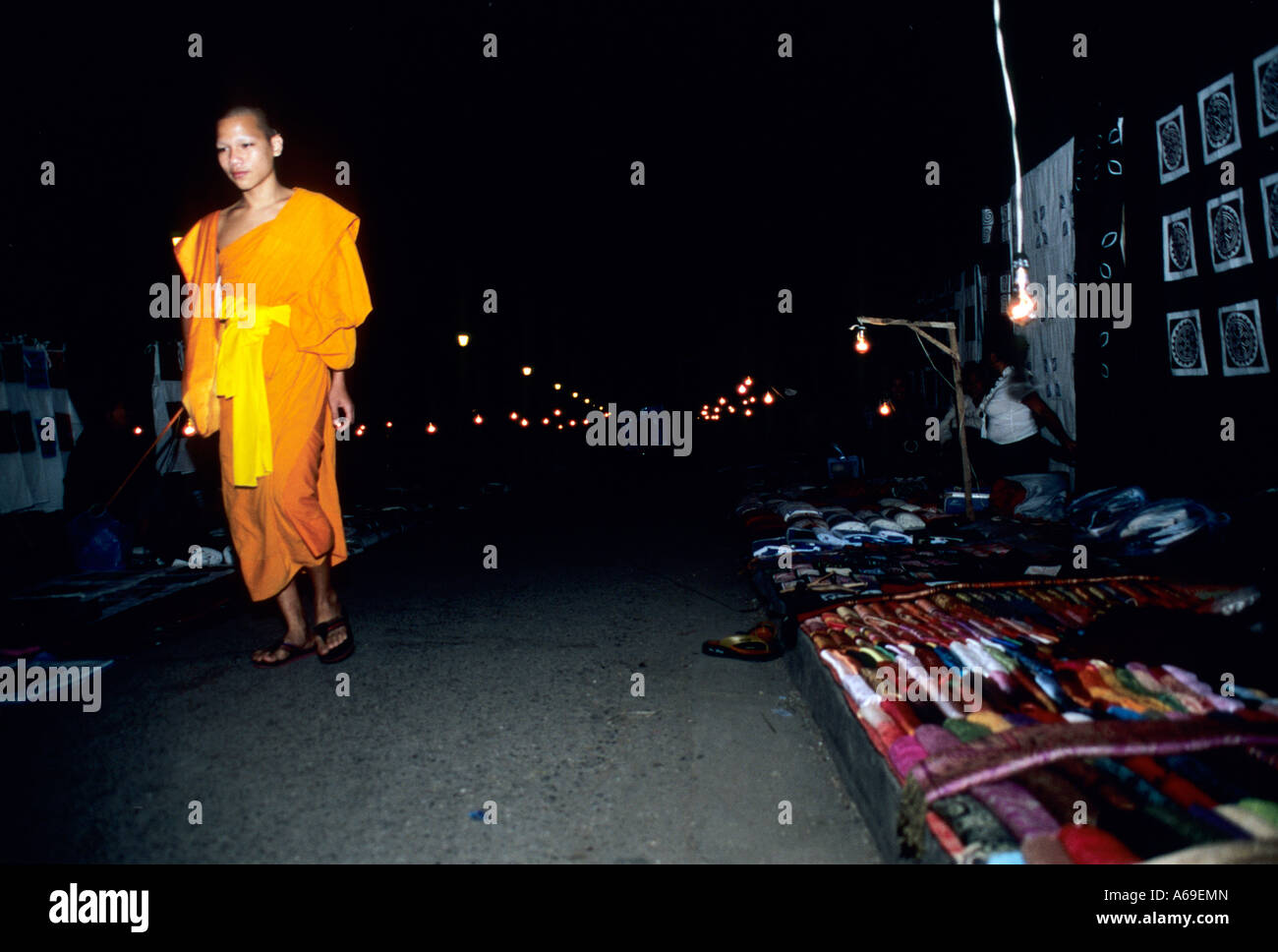 Buddhist monk strolling along the stalls with colorful textiles on the ...