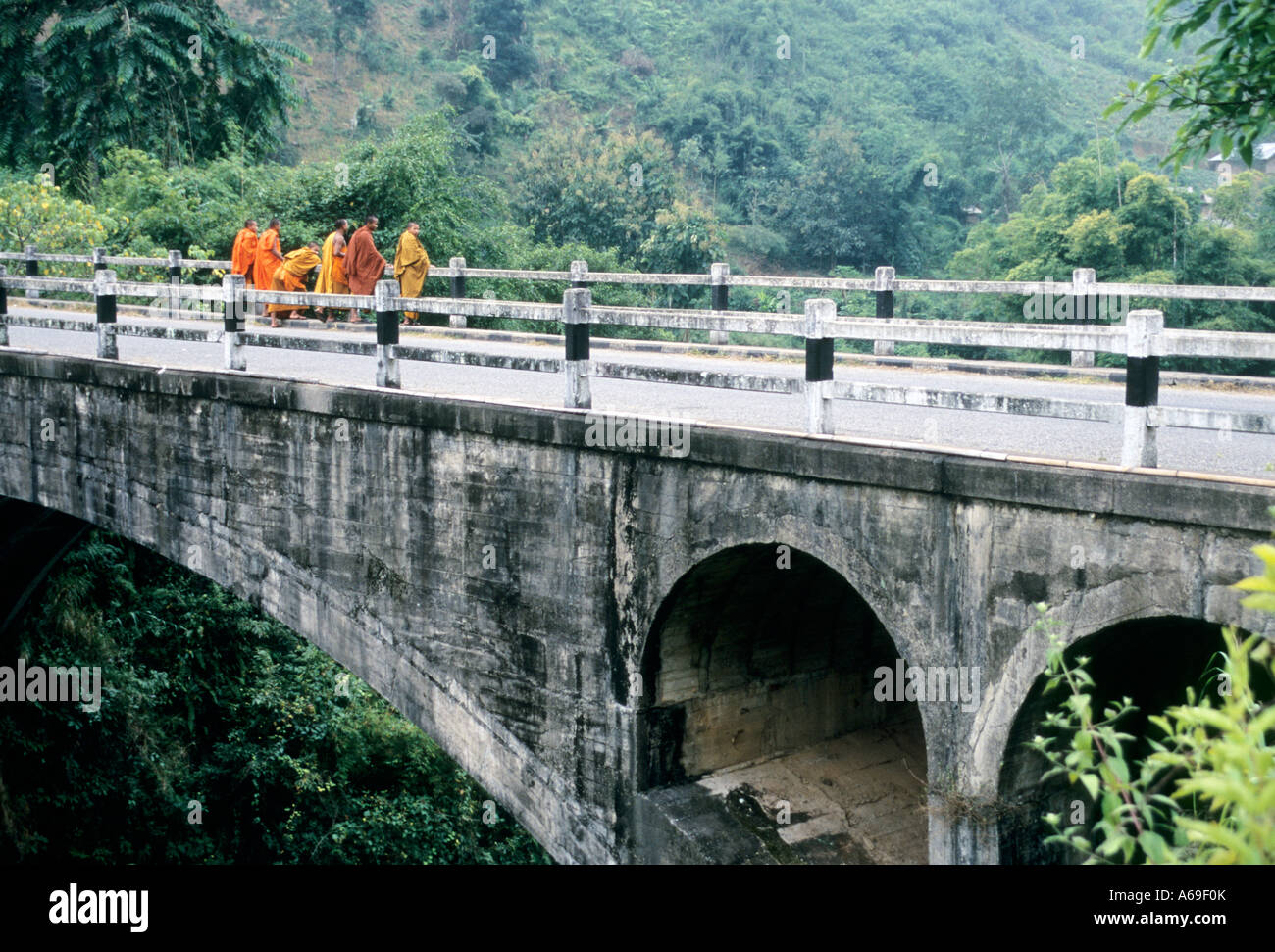 Group of orange robed monks on a bridge. Laos Stock Photo - Alamy