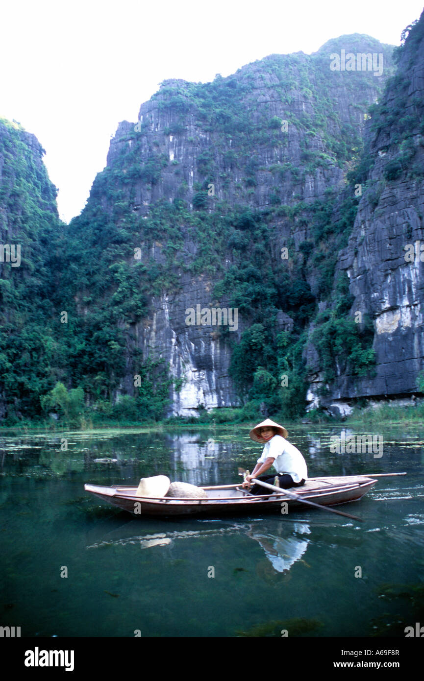 Person in rowboat on Ngo Dong River between high rising karst rocks ...