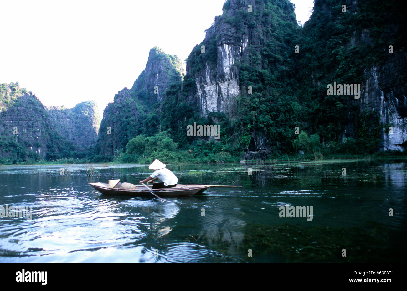 Person in rowboat on Ngo Dong River between high rising karst rocks ...