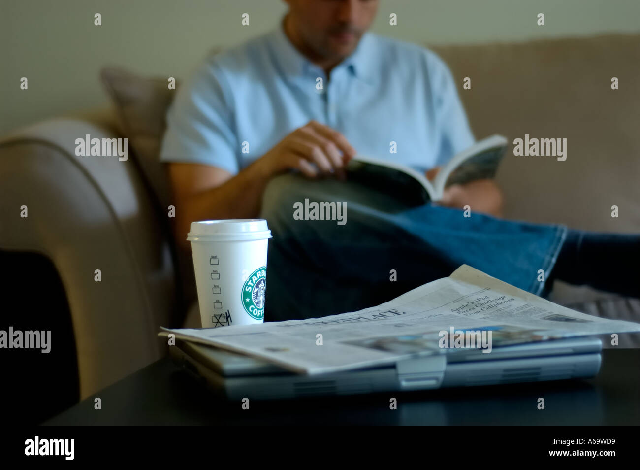 Starbucks coffee cup on coffee table Laptop and newspaper on table too ...