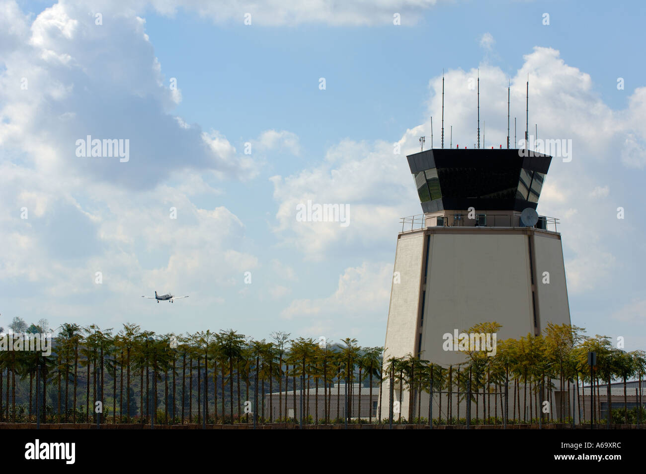 Airport traffic control tower at sunset with small airplane taking off ...