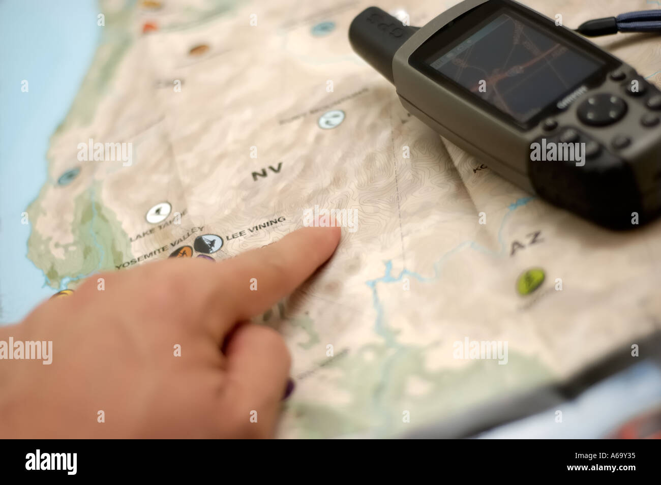 GPS laid out on a topo map and hand pointing on map Stock Photo - Alamy