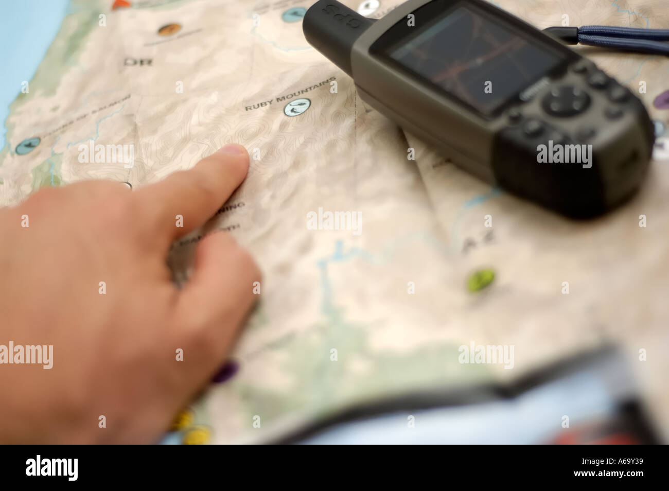 GPS laid out on a topo map and hand pointing on map Stock Photo - Alamy