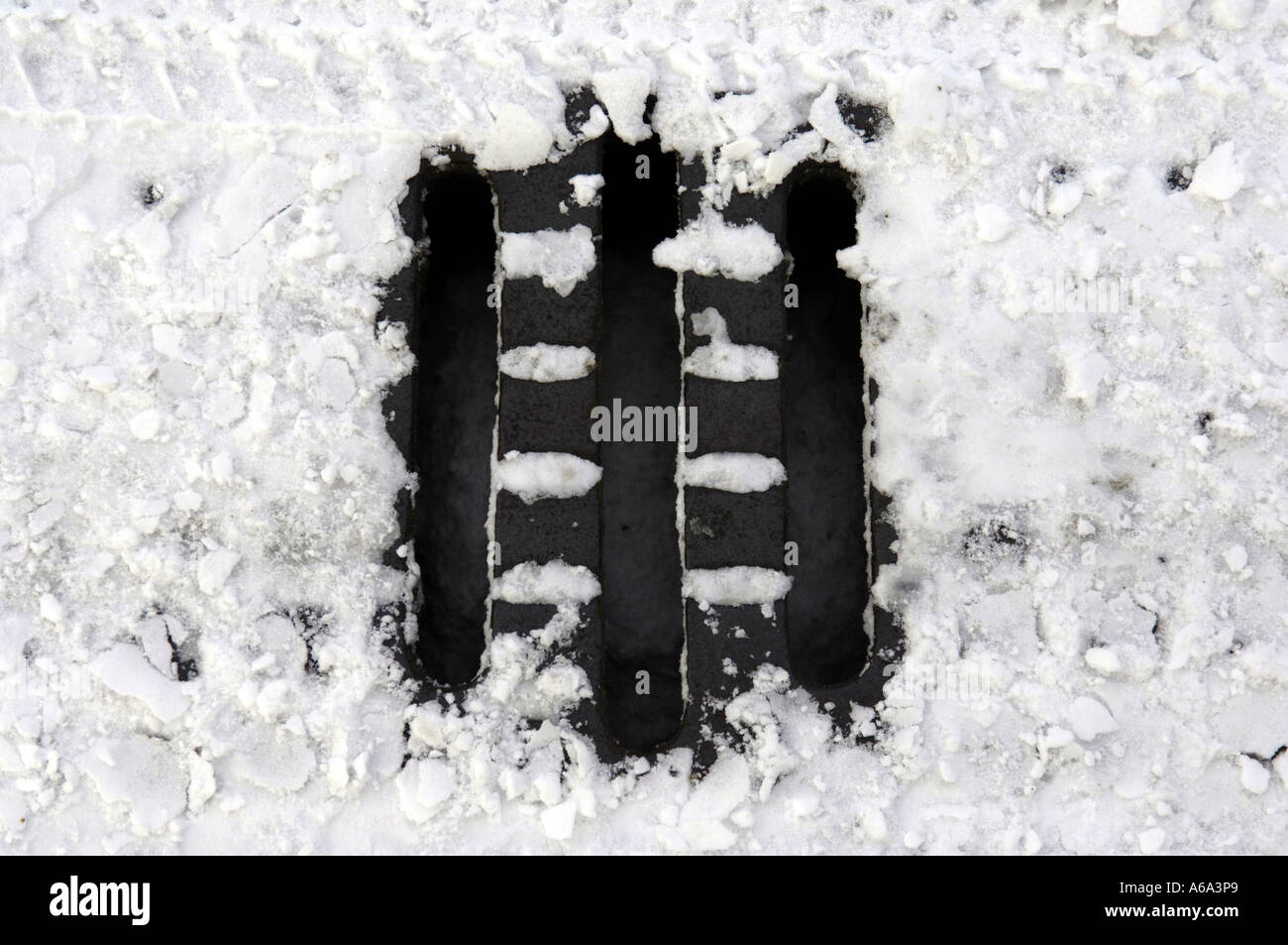 snow covered grid drain floor roadside road winter wintry ice cold ...